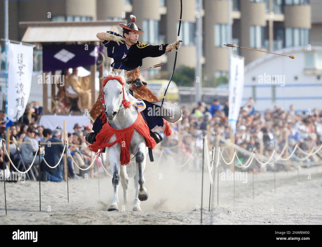 An archer clad in traditional Japanese costume shoots an arrow at a ...