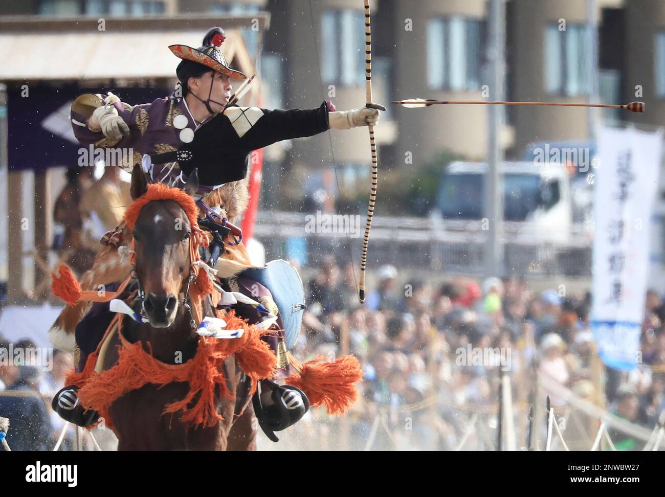 An archer clad in traditional Japanese costume shoots an arrow at a ...