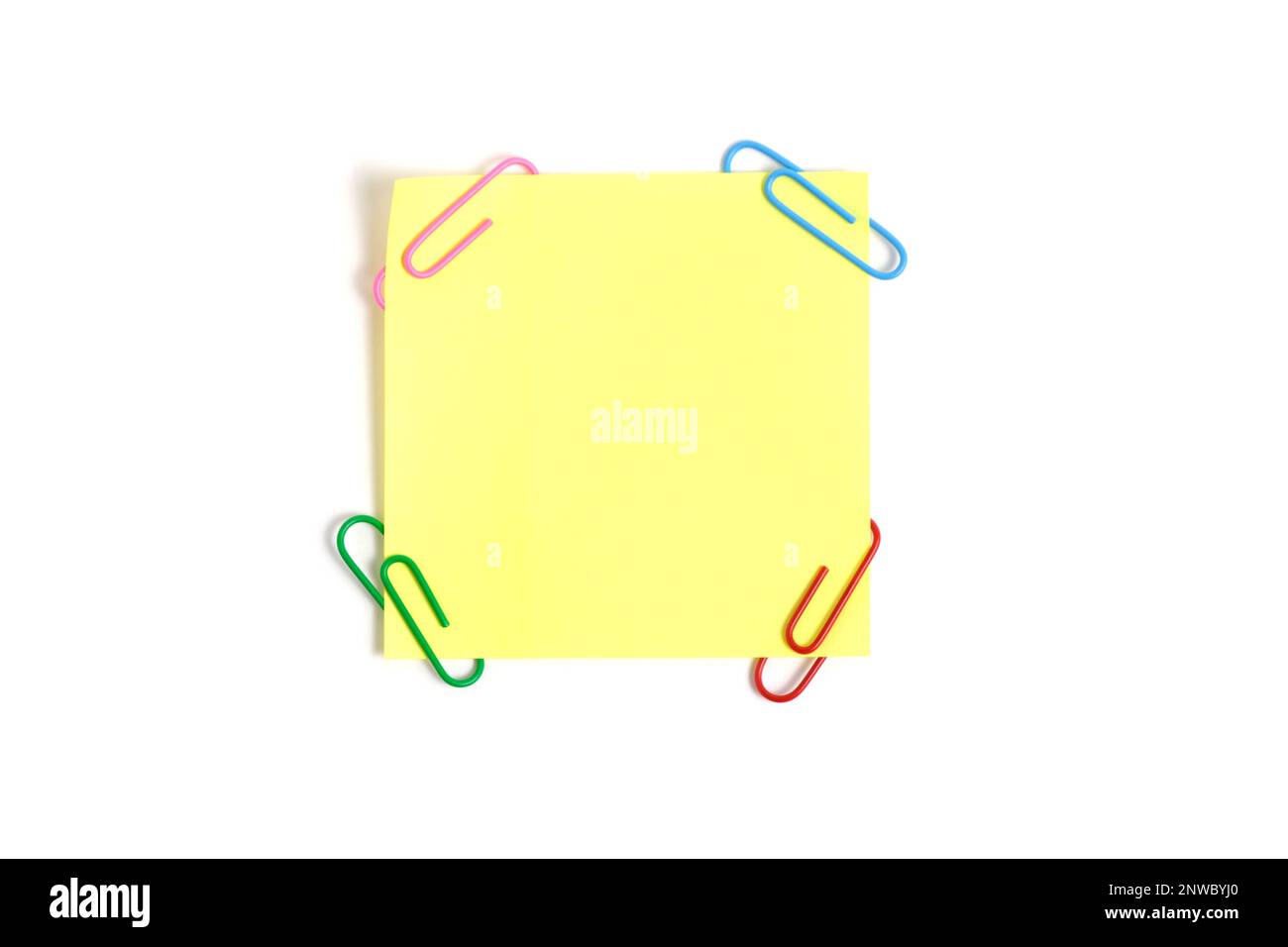 Yellow paper sticker for written notes and paper clips on a white ...