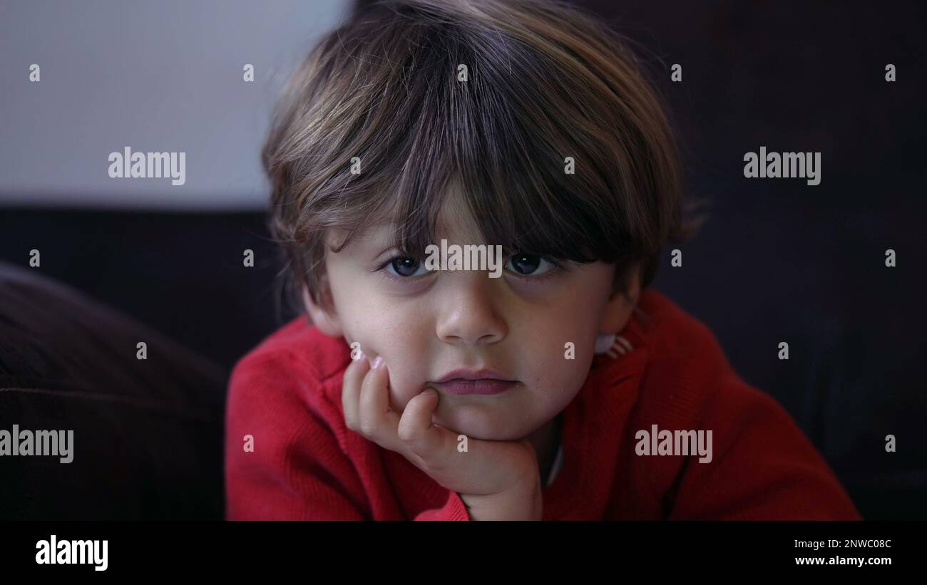 One small boy closeup face with hand in chin watching cartoons off ...