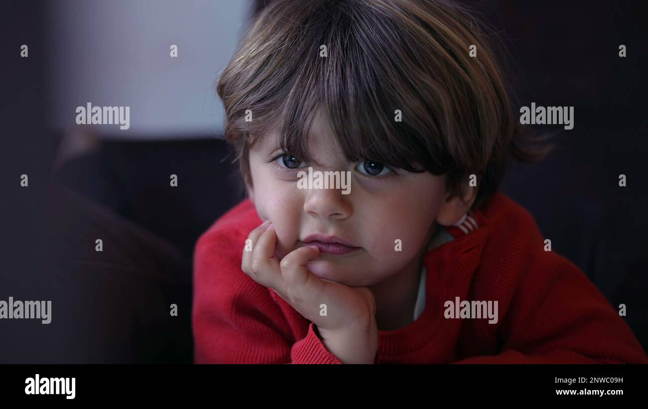 One small boy closeup face with hand in chin watching cartoons off ...