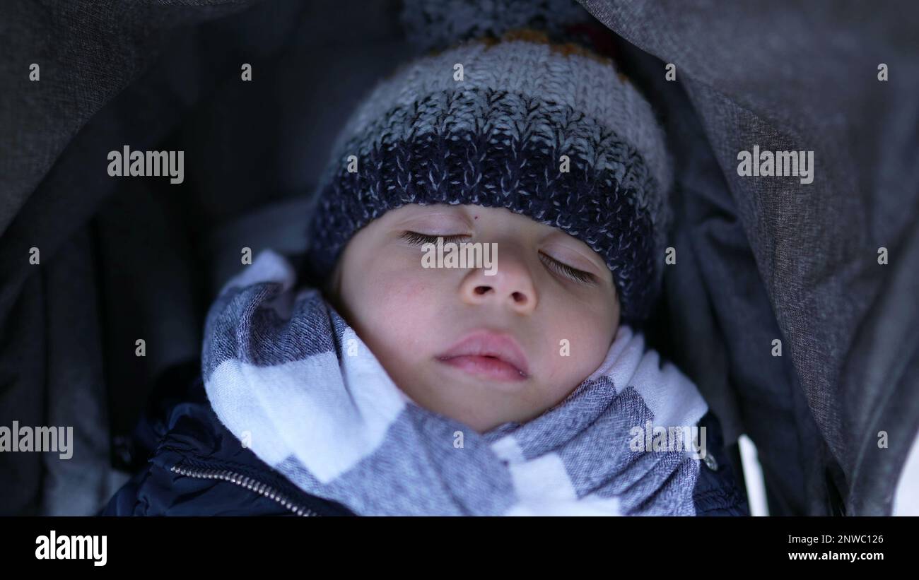 Child asleep wearing winter clothes inside stroller. Sleeping baby ...