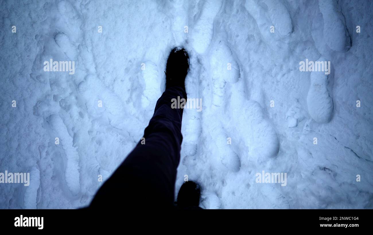 Feet walking on snow POV perspective of boots stepping in winter season ...