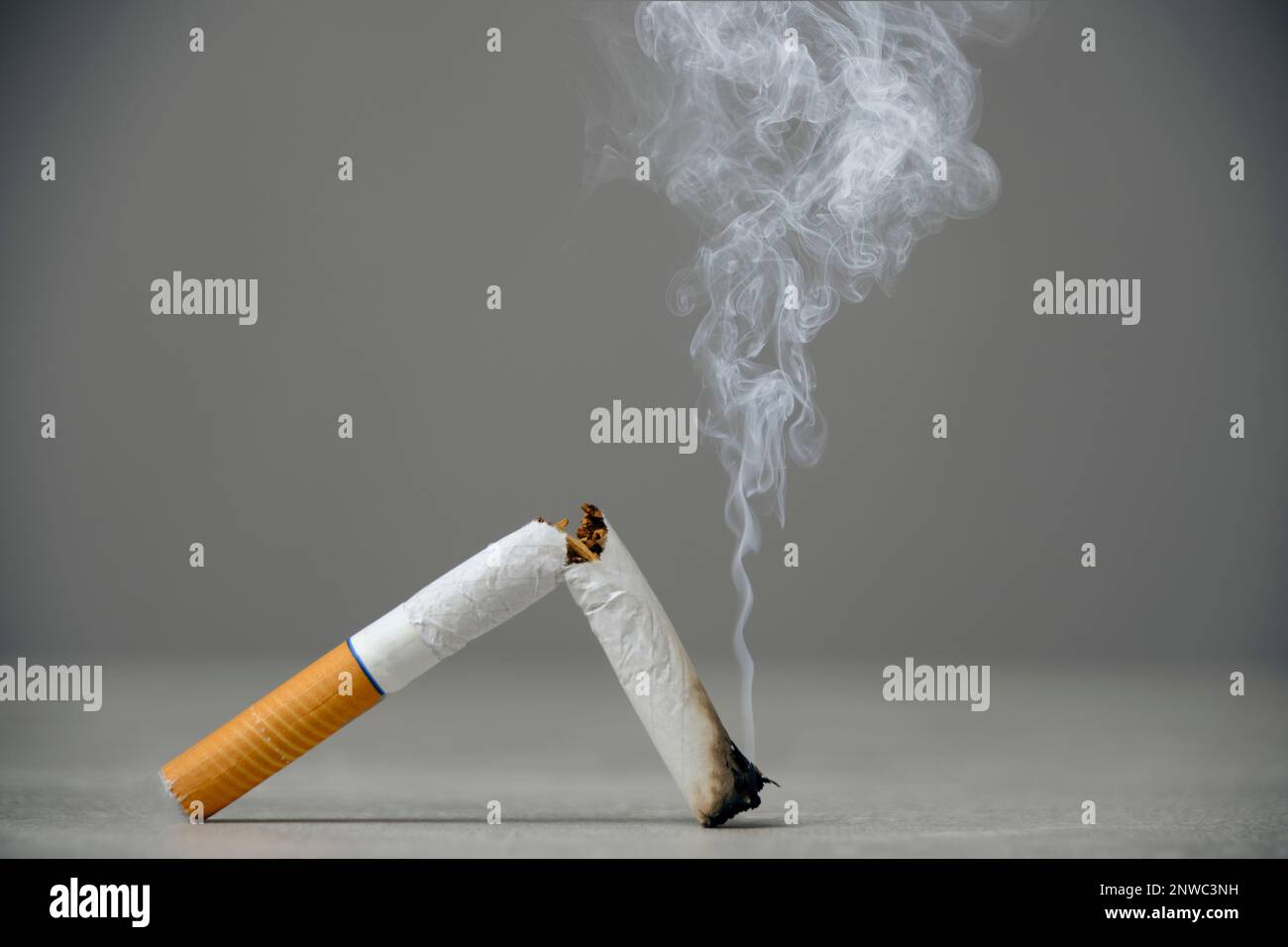 Broken smoking cigarette gray background Stock Photo - Alamy
