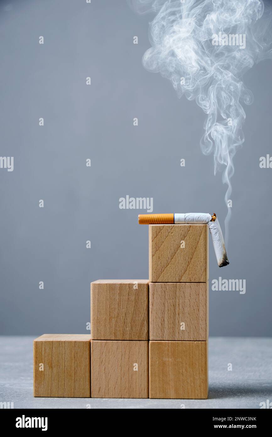 Top wooden ladder of cubes lies a broken, smoking cigarette.Concept ...