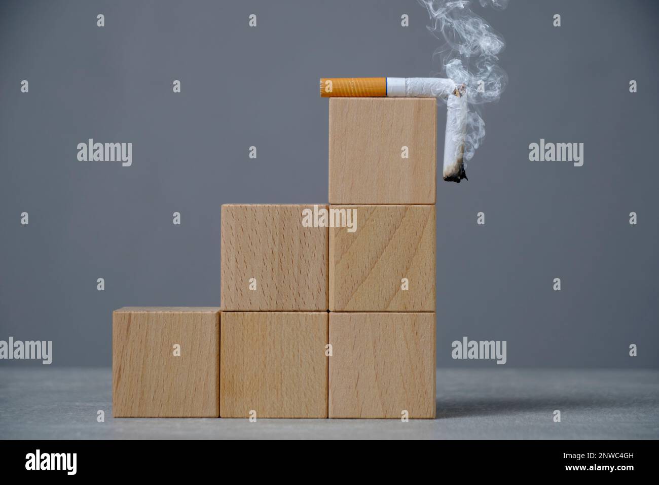 Top wooden ladder of cubes lies a broken, smoking cigarette.Concept ...