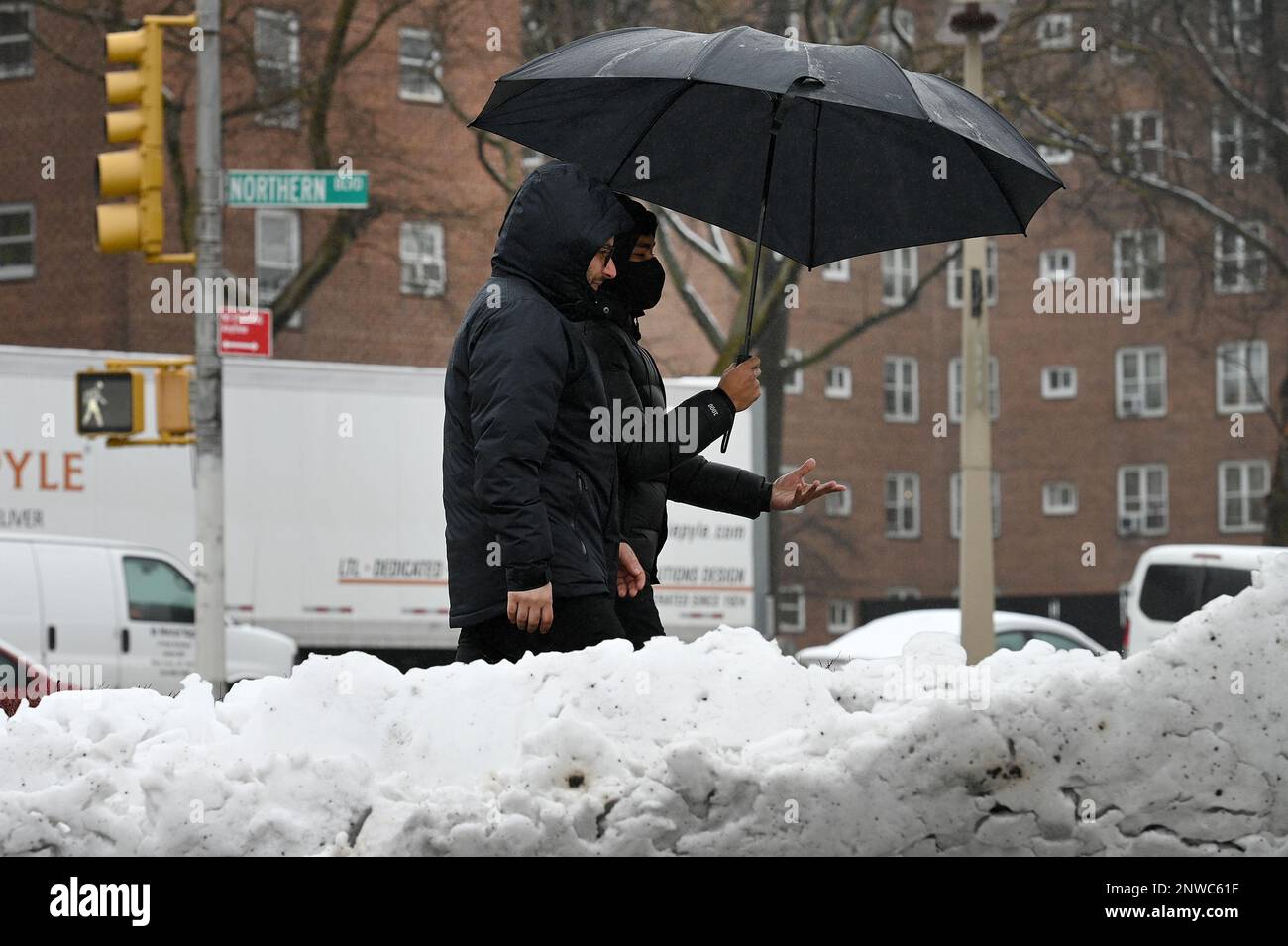 New York, USA. 28th Feb, 2023. Two people walk past a berm of snow ...