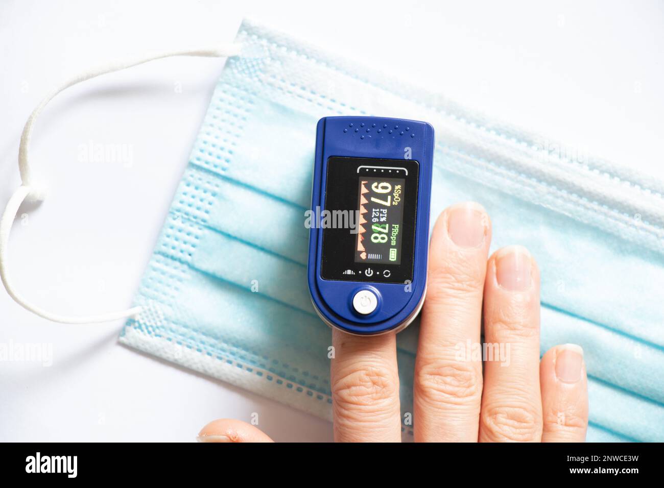 woman's finger pulse oximeter and disposable medical mask on isolated ...