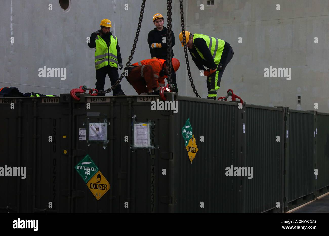 Contractors inspect and latch a crane onto a shipping container on the ...
