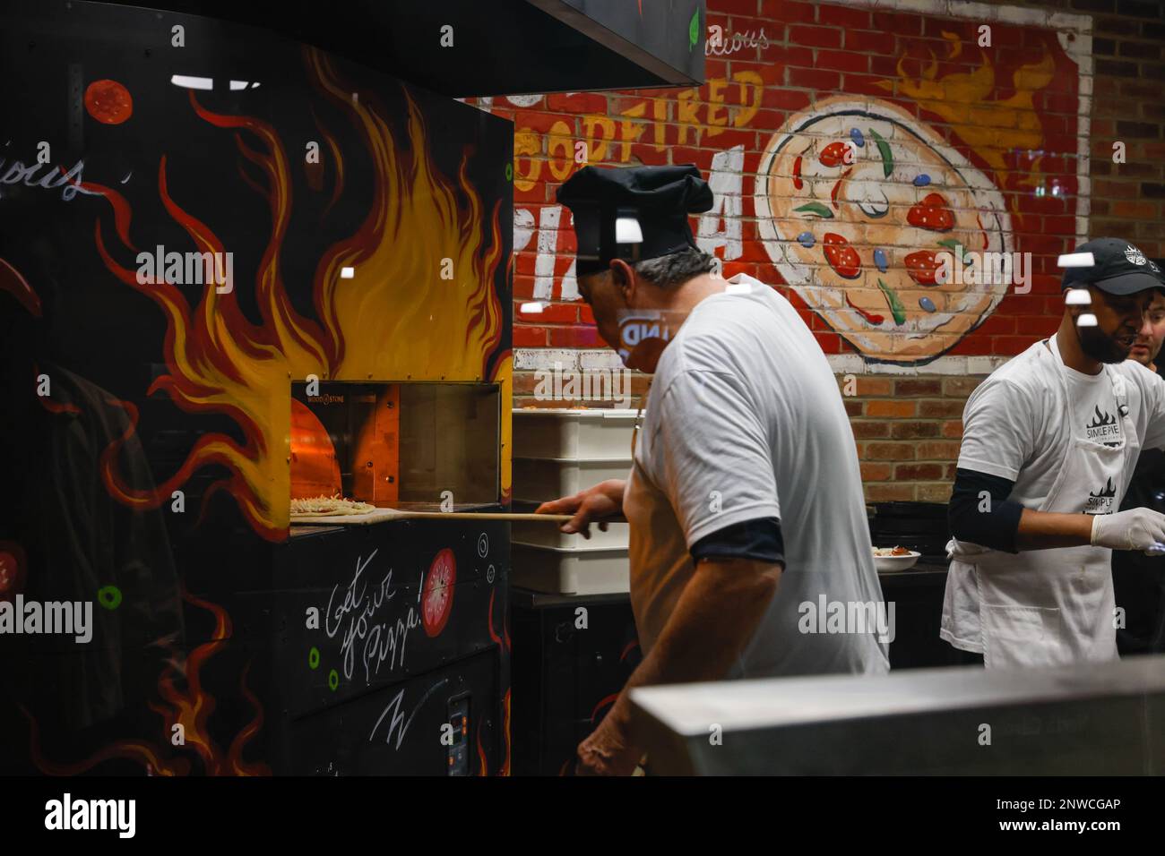 Workers prepare pizza in the wood-fire pizza oven at the Cherry Point ...