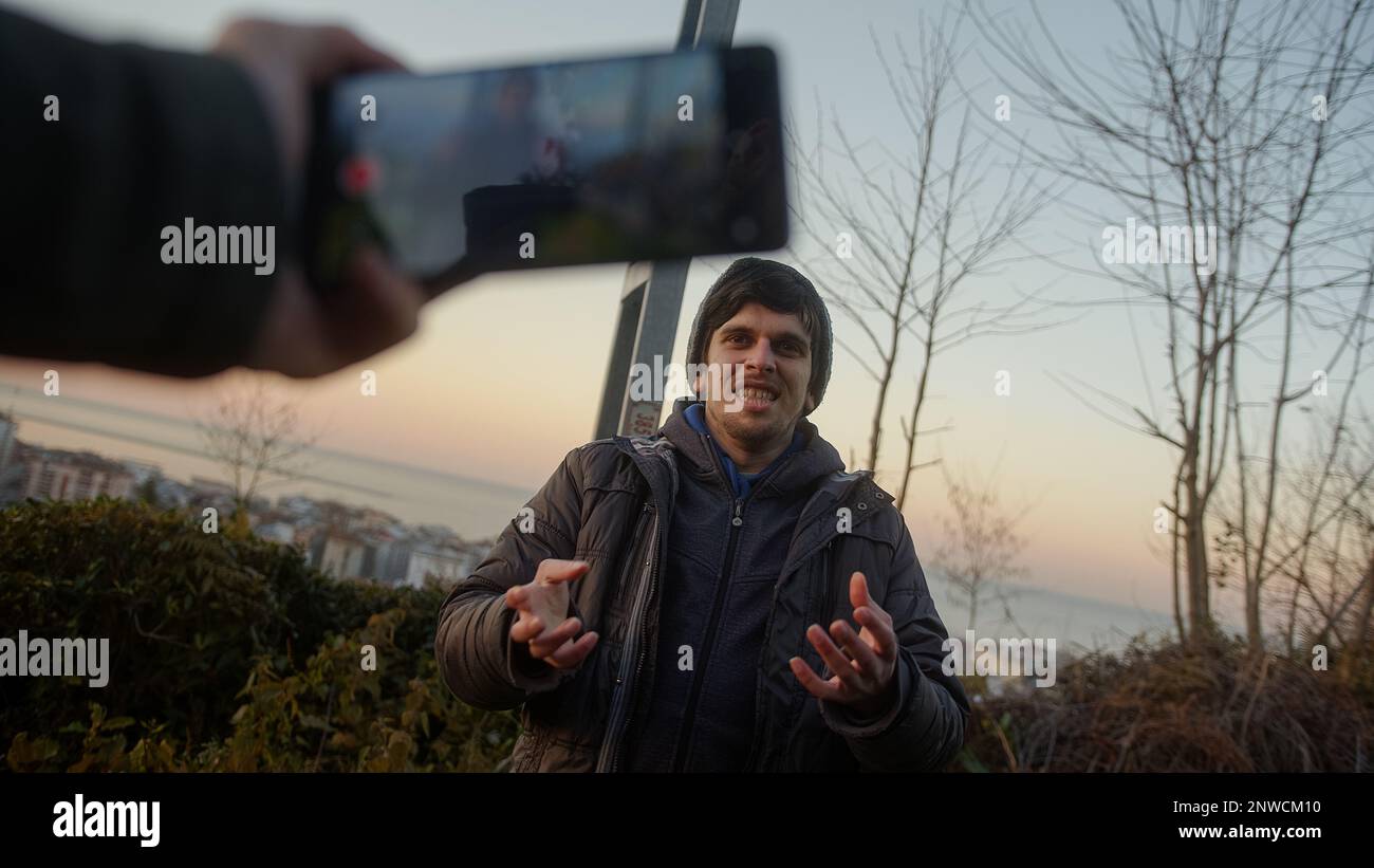 A Handsome Male Influencer Captures Video with Phone in Beautiful Green ...