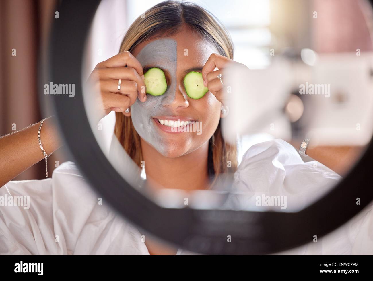 Woman, vlogger and ring light of skincare influencer holding cucumber ...