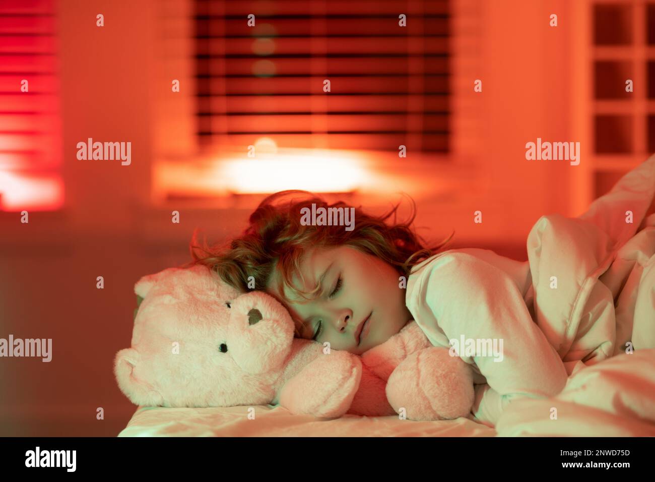 Kid enjoying sweet dreams. Kid sleeping in bed with a toy teddy bear ...