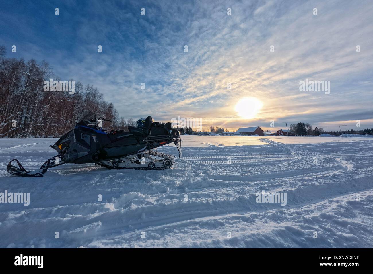 Snowmobile, helmet on snow field at forest side, sunset Sun, cloudy ...