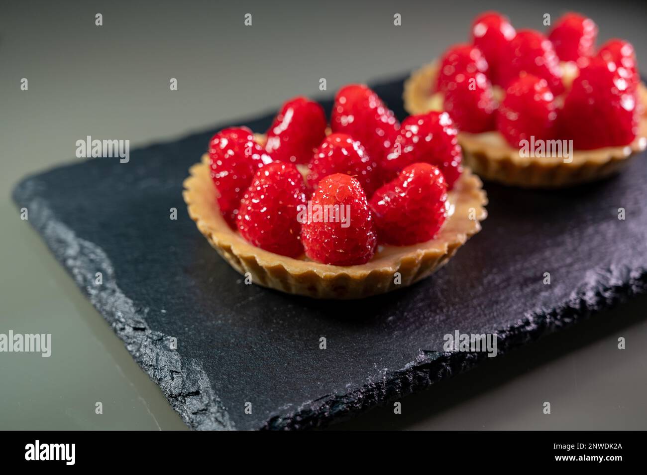 Artisanal baked small tart with cream and fresh ripe red raspberry ...