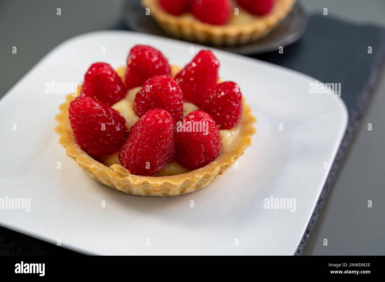 Artisanal baked small tart with cream and fresh ripe red raspberry ...
