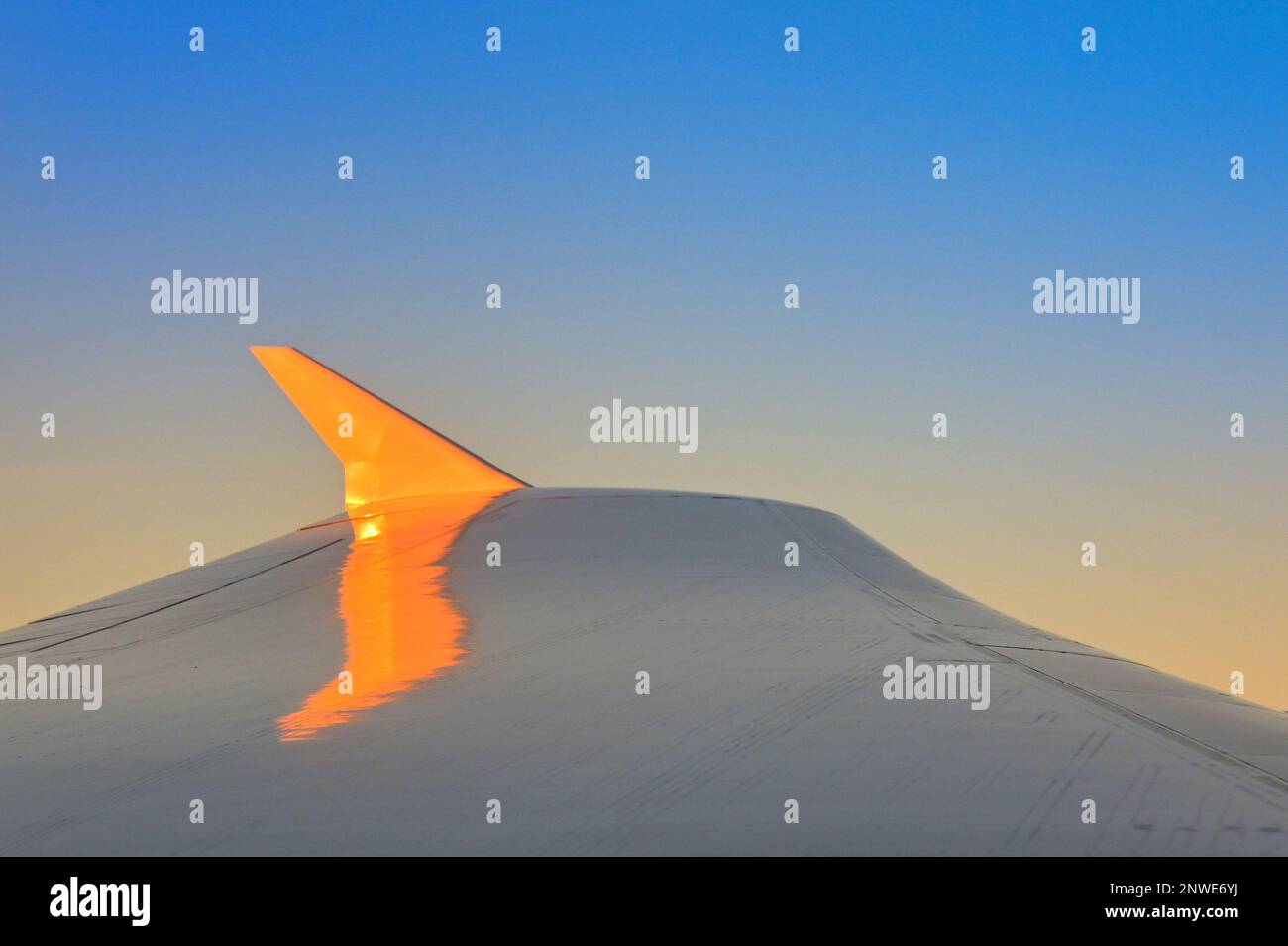 Wing and curved wing tip of a modern passenger jet in flight at sunset ...