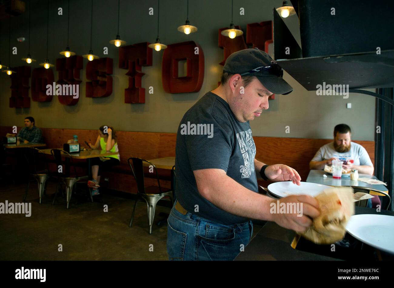 In this Thursday, June 21, 2018 photo, Aaron Glick buses tables while ...