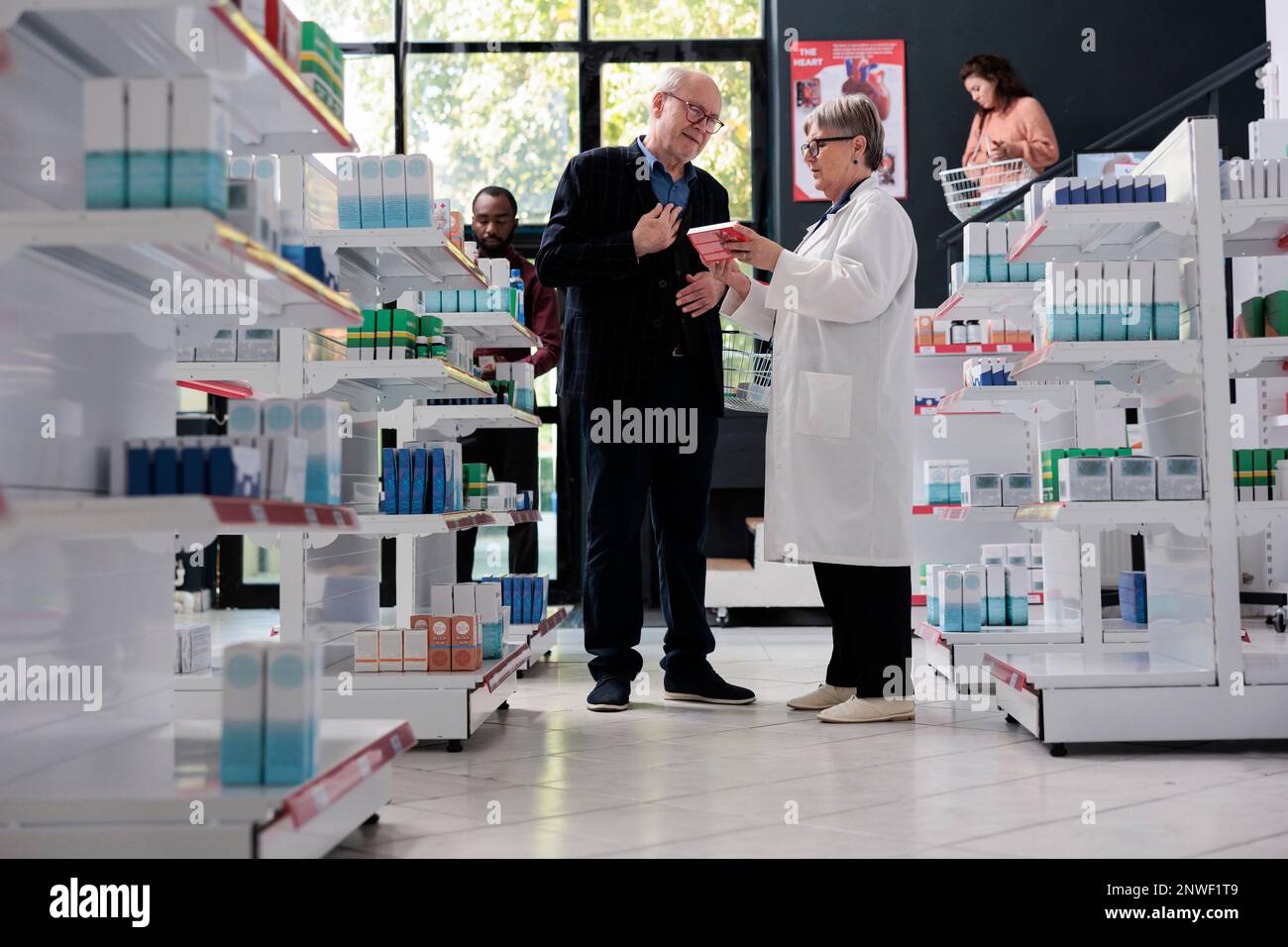 Senior drugstore employee helping customer with pharmaceutical products ...