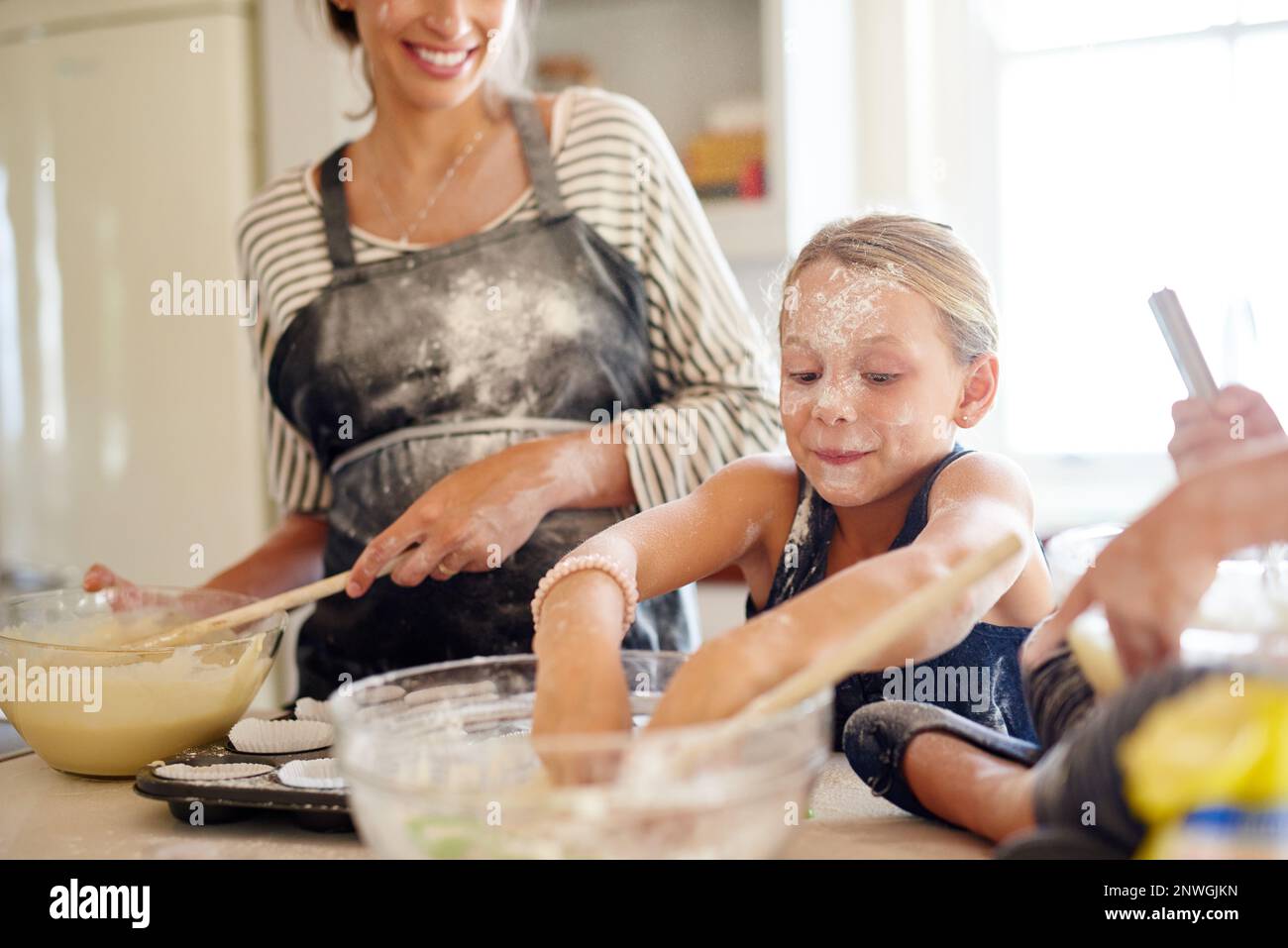 Baking up a storm. Shot of two little girls baking with their mother in ...