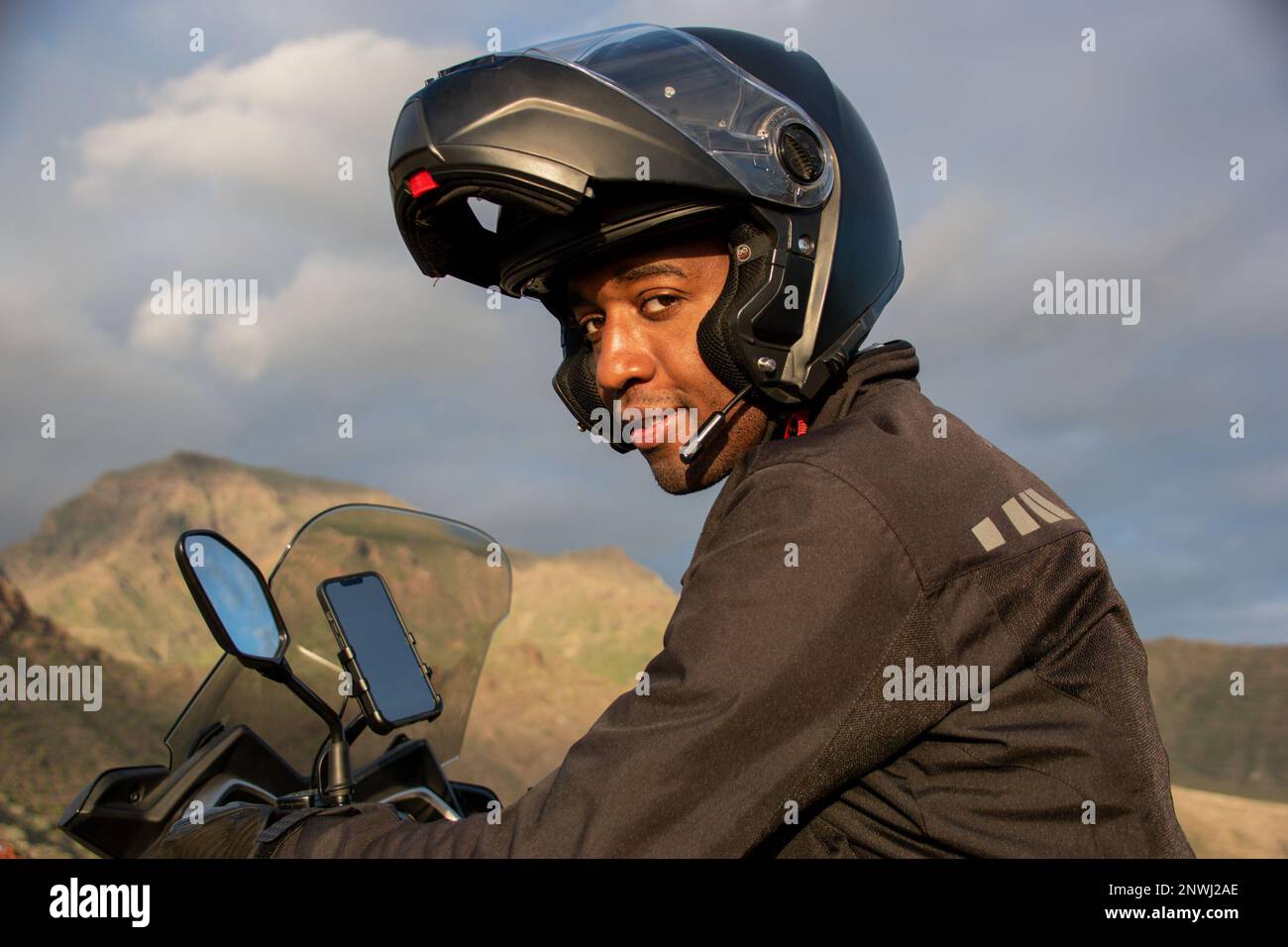 African American biker on his motorcycle equipped with a smartphone ...