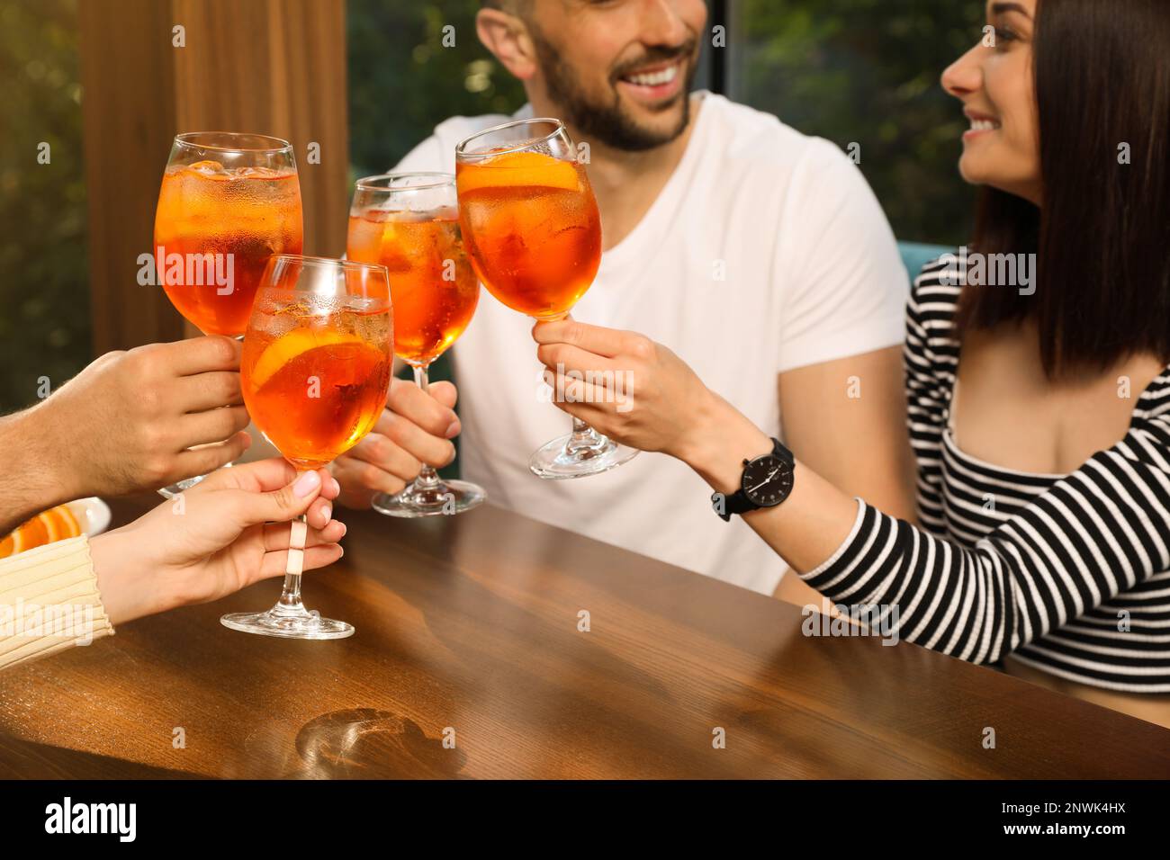 Friends clinking glasses of Aperol spritz cocktails at table, closeup ...