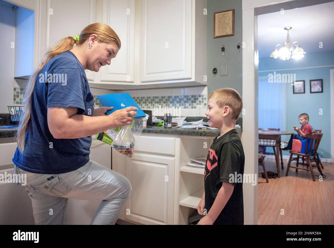 In this undated photo Jennifer Deuel, left, hands school supplies to ...
