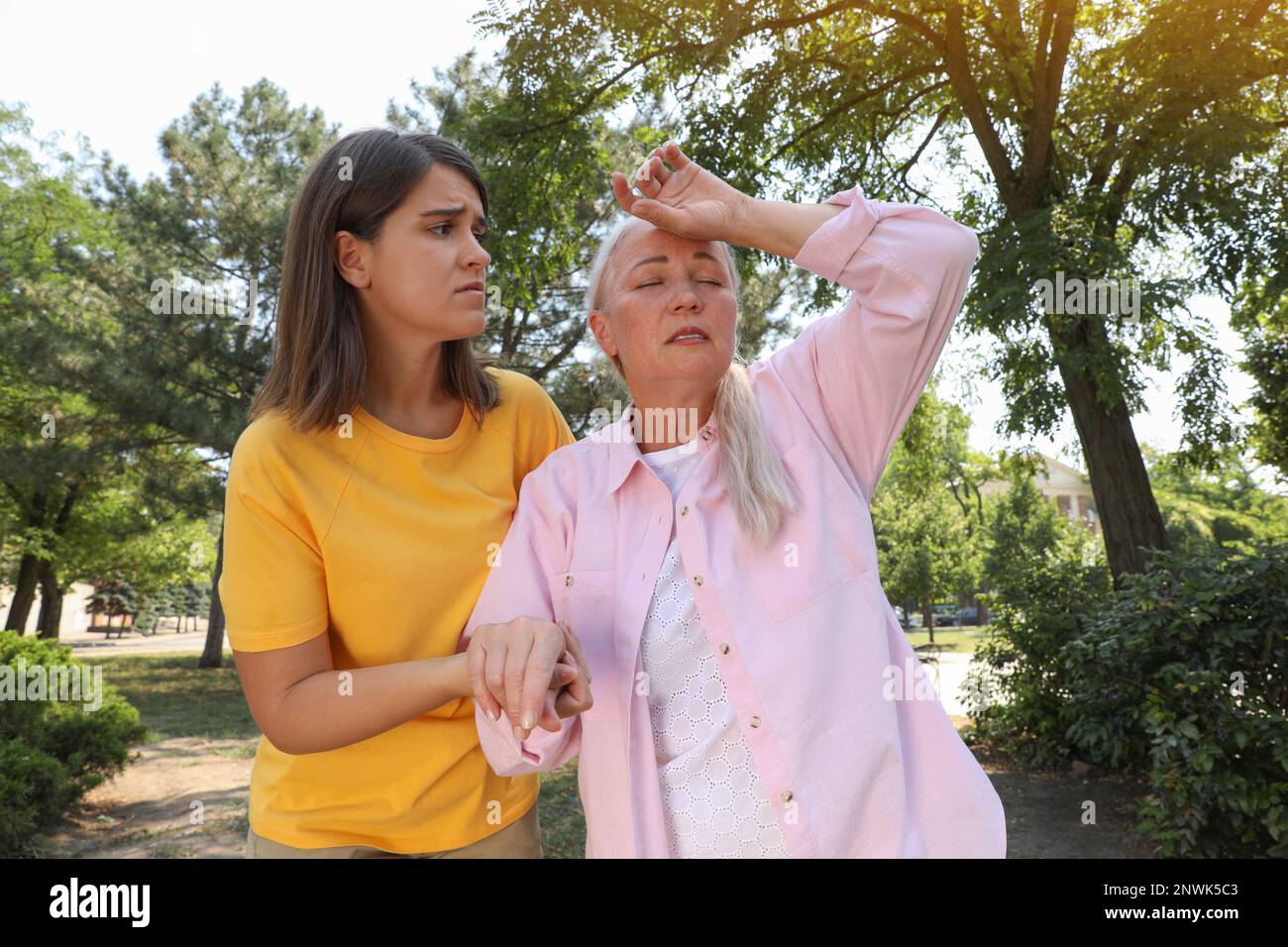 Woman helping mature lady in park. Suffering from heat stroke Stock ...
