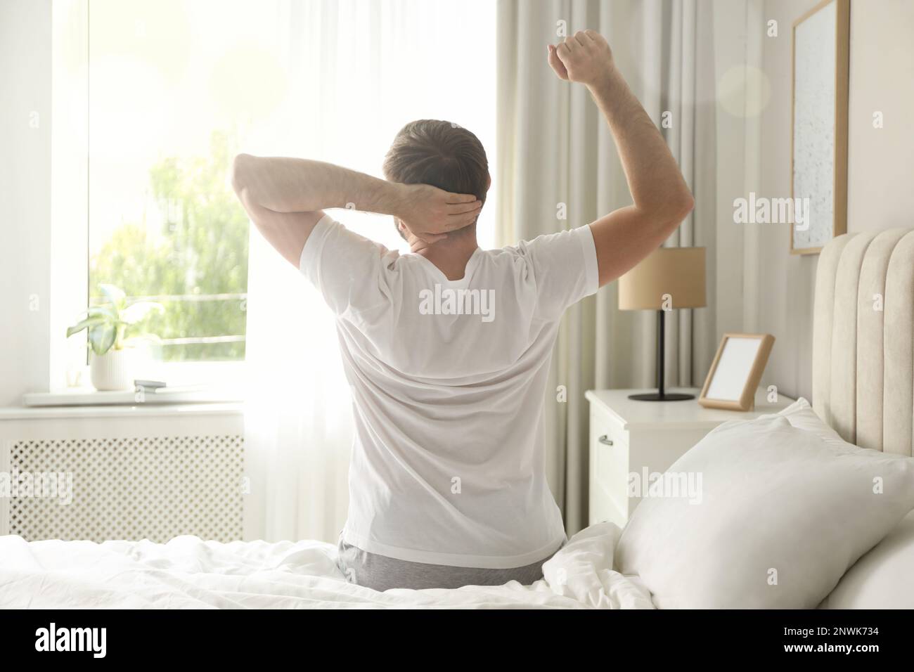 Man stretching on bed at home, back view Stock Photo - Alamy