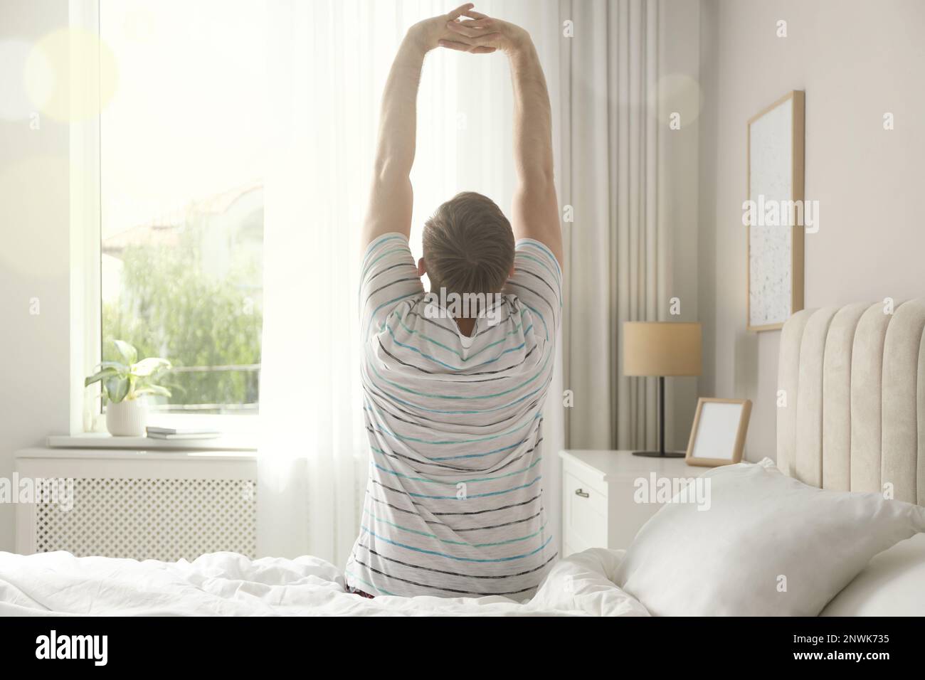 Man stretching on bed at home, back view Stock Photo - Alamy