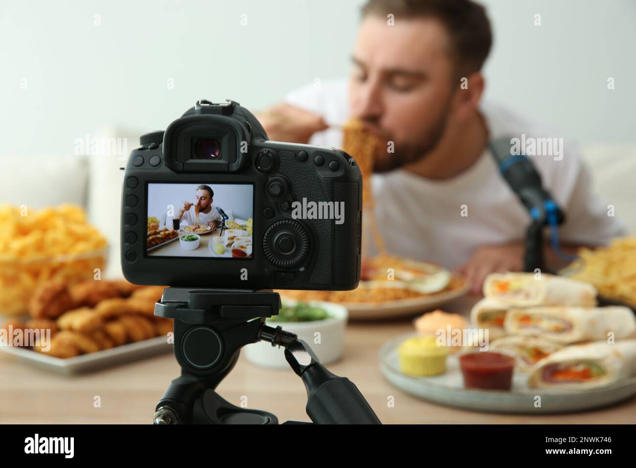 Food blogger recording eating show against light background, focus on ...