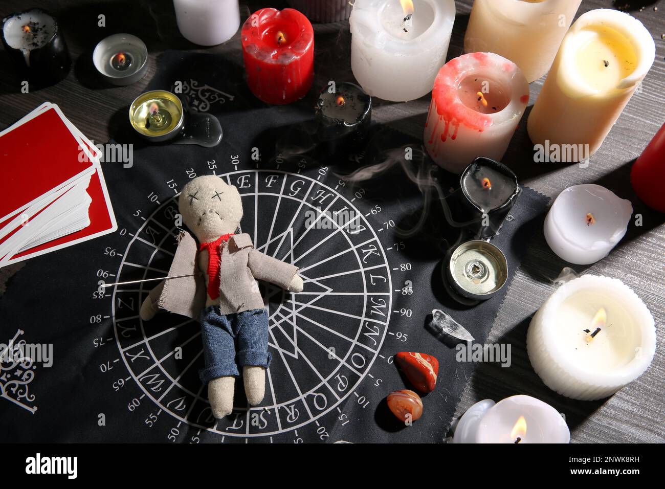 Voodoo doll pierced with needle surrounded by ceremonial items on table ...