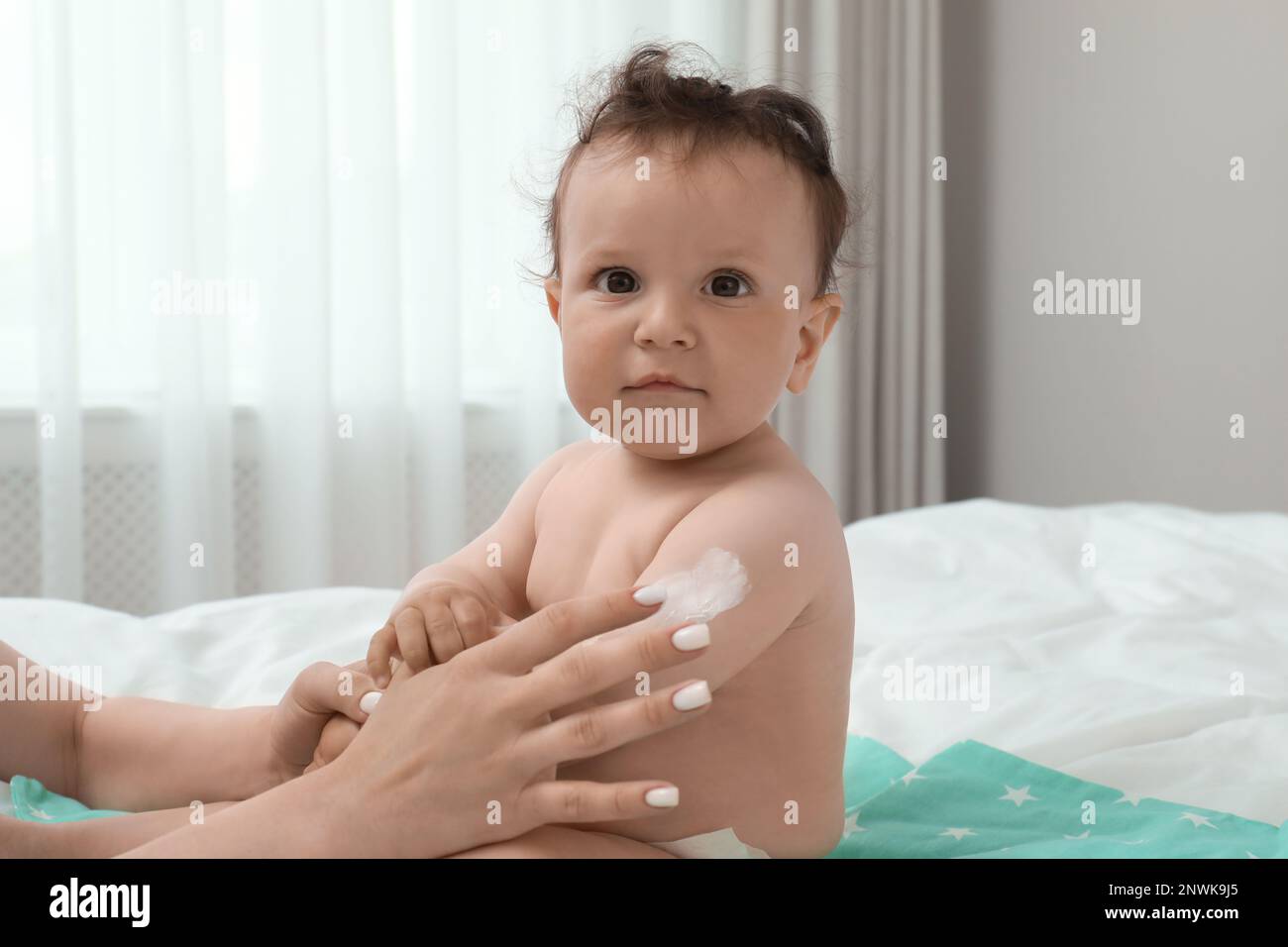 Mother applying body cream on her baby in bedroom Stock Photo - Alamy
