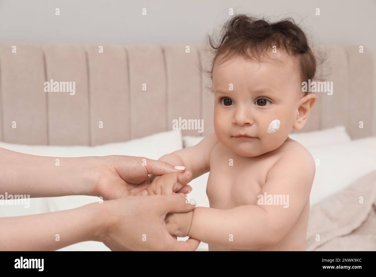 Mother applying body cream on her baby in bedroom Stock Photo - Alamy