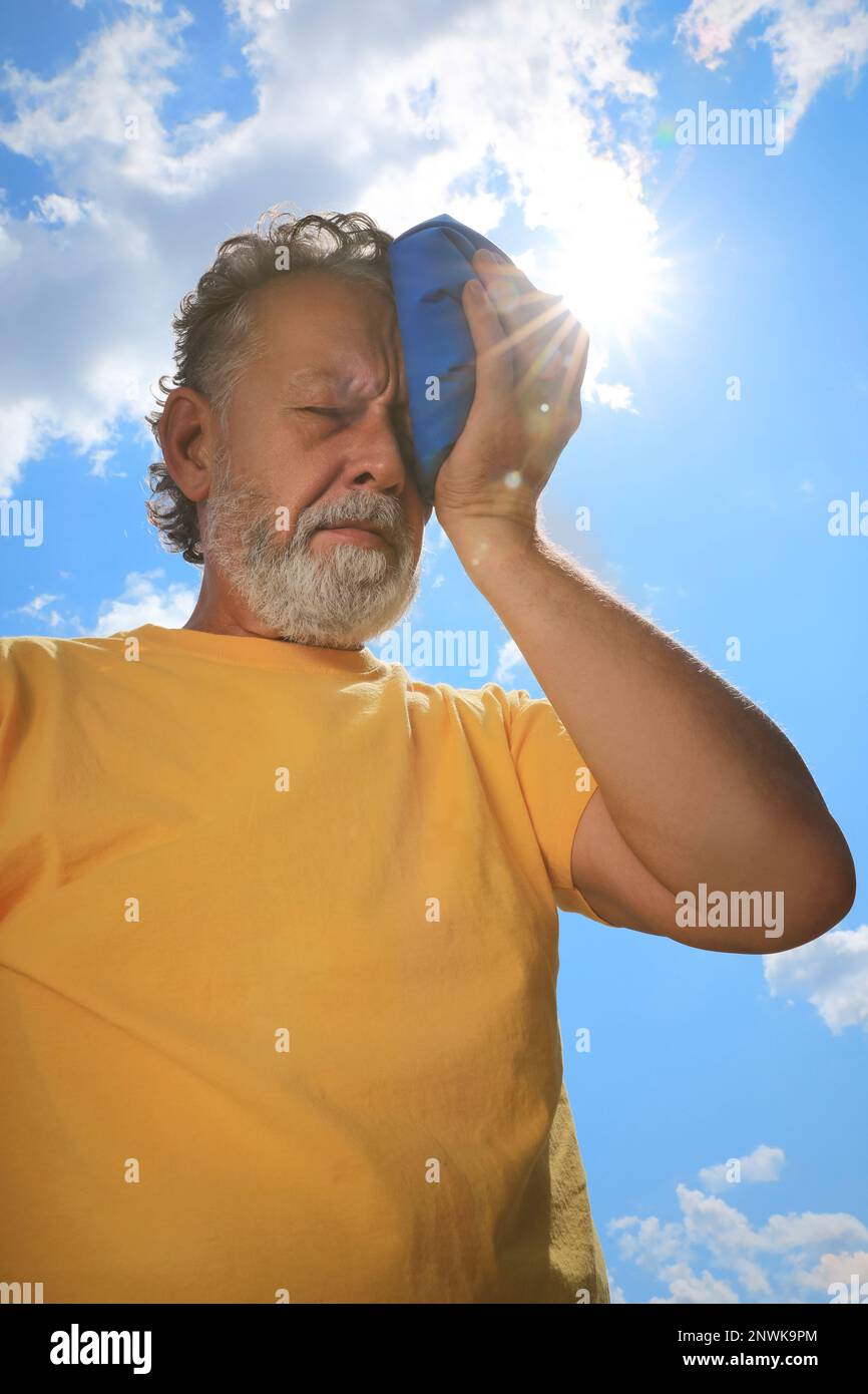 Senior man with cold pack suffering from heat stroke outdoors, low ...