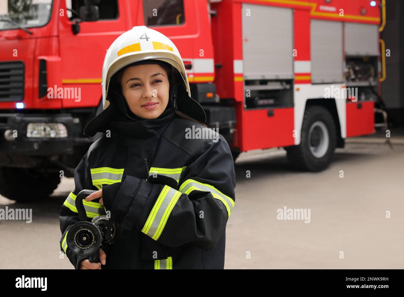 Firefighter in uniform with high pressure water jet near fire truck ...