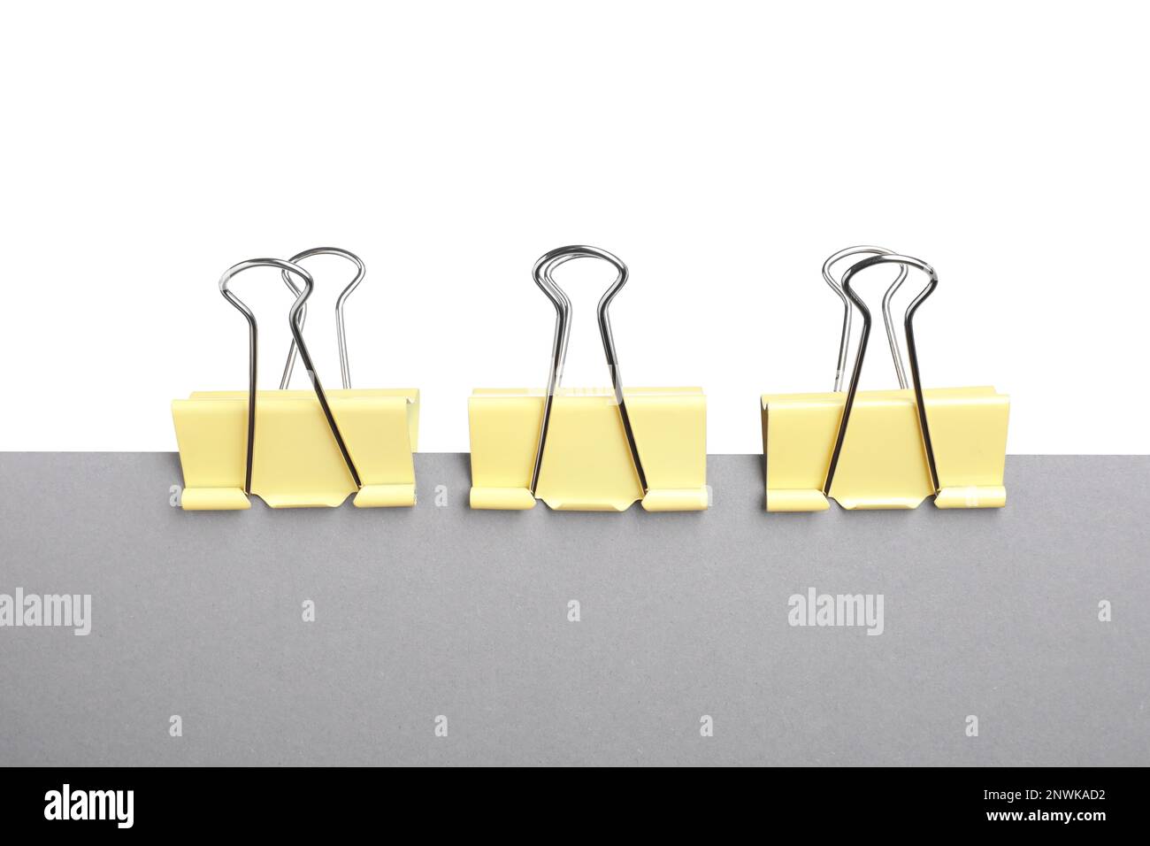 Grey paper with yellow binder clips isolated on white Stock Photo - Alamy