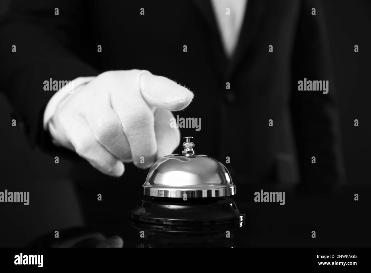 Butler ringing service bell at table on black background, closeup Stock ...
