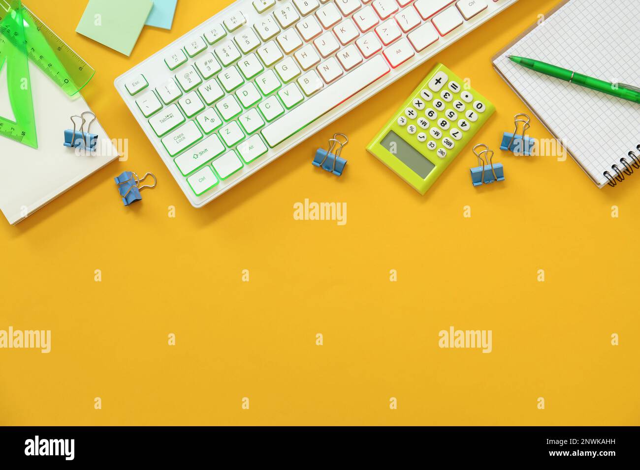 Modern keyboard with RGB lighting and stationery on yellow background ...