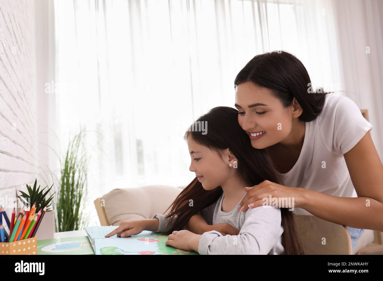 Happy mother and daughter reading book together at home. Single ...