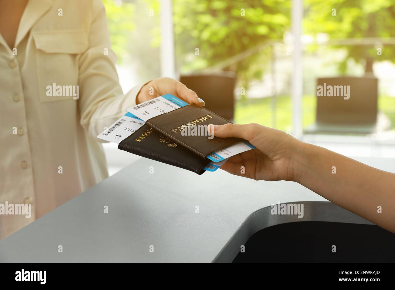 Agent giving passports and tickets to woman at check-in desk in airport ...