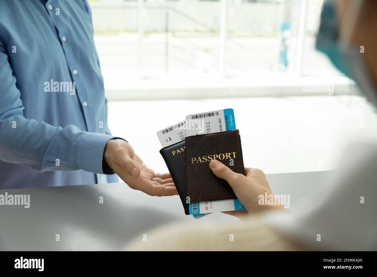 Agent giving passports and tickets to man at check-in desk in airport ...
