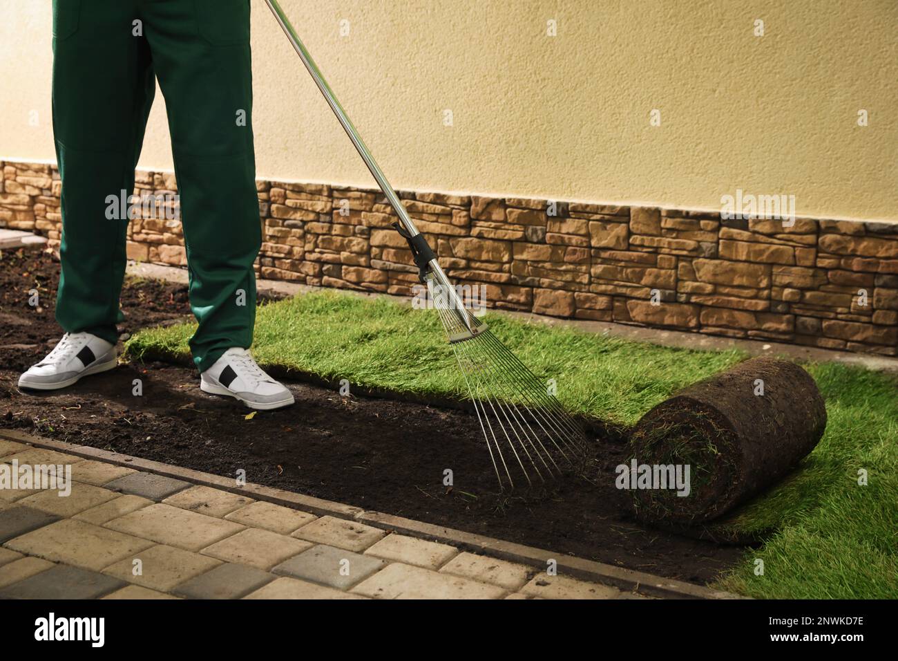 Worker leveling soil before laying grass sod at backyard, closeup Stock ...