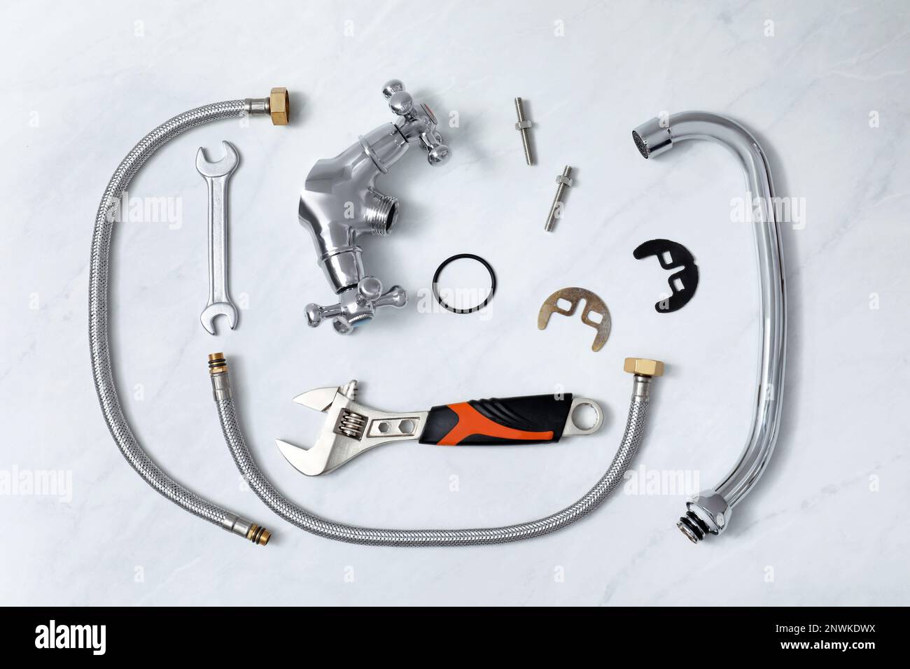 Parts of water tap and wrenches on white marble countertop, flat lay ...