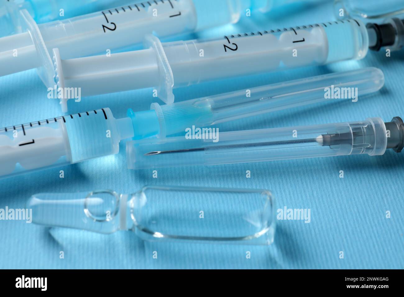 Disposable syringes with needles and ampule on light blue background ...