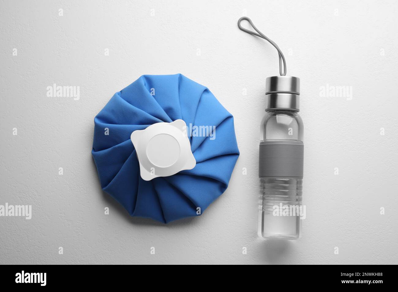 Bottle of water and cold compress on white background, flat lay. Heat ...