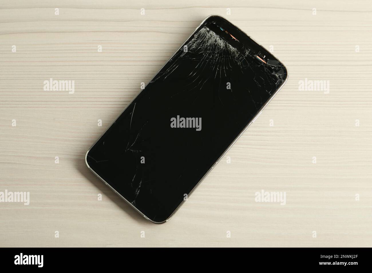 Smartphone with cracked screen on white wooden table, top view. Device ...