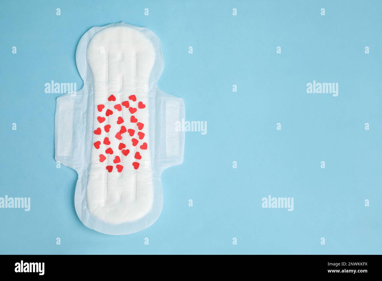 Menstrual pad with confetti on light blue background, top view. Space ...
