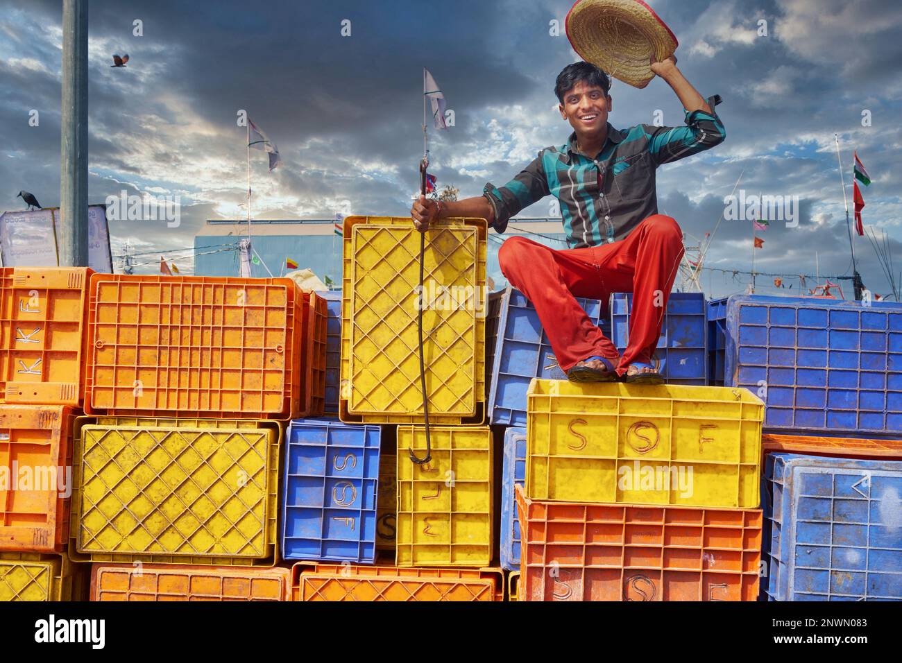 A young Indian man sitting on colorful plastic crates in the Old Port ...