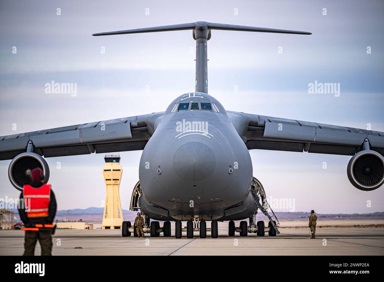 Crews await for a C-5 Super Galaxy's front ramp to lift on the ramp at ...